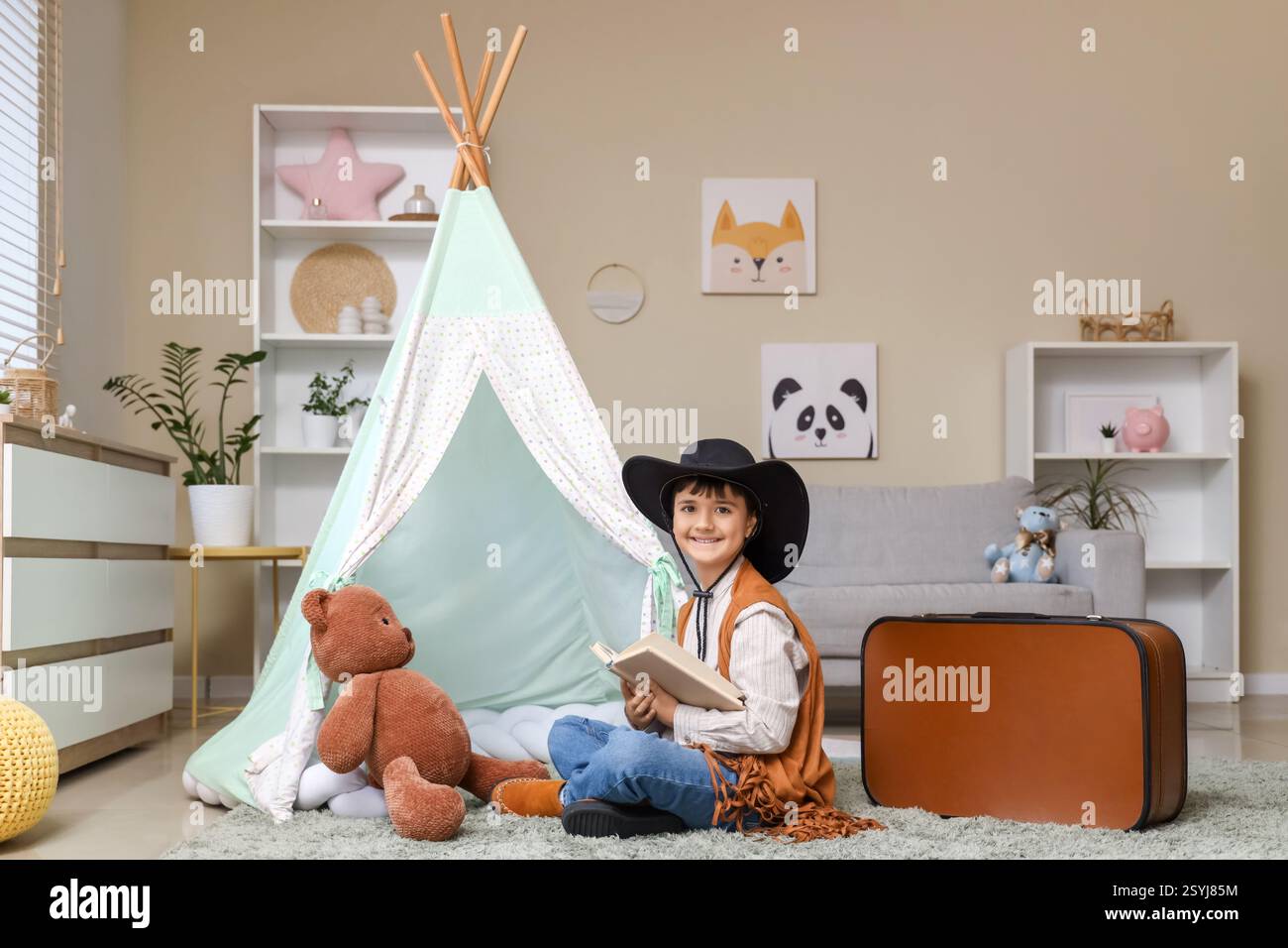 Cute boy dressed as cowboy reading adventure book at home Stock Photo ...