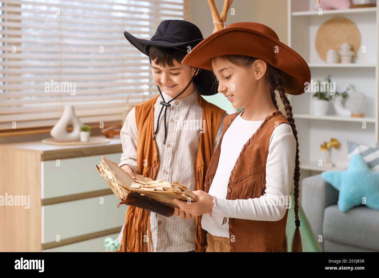 Cute children dressed as cowboys reading adventure book at home Stock Photo - Alamy