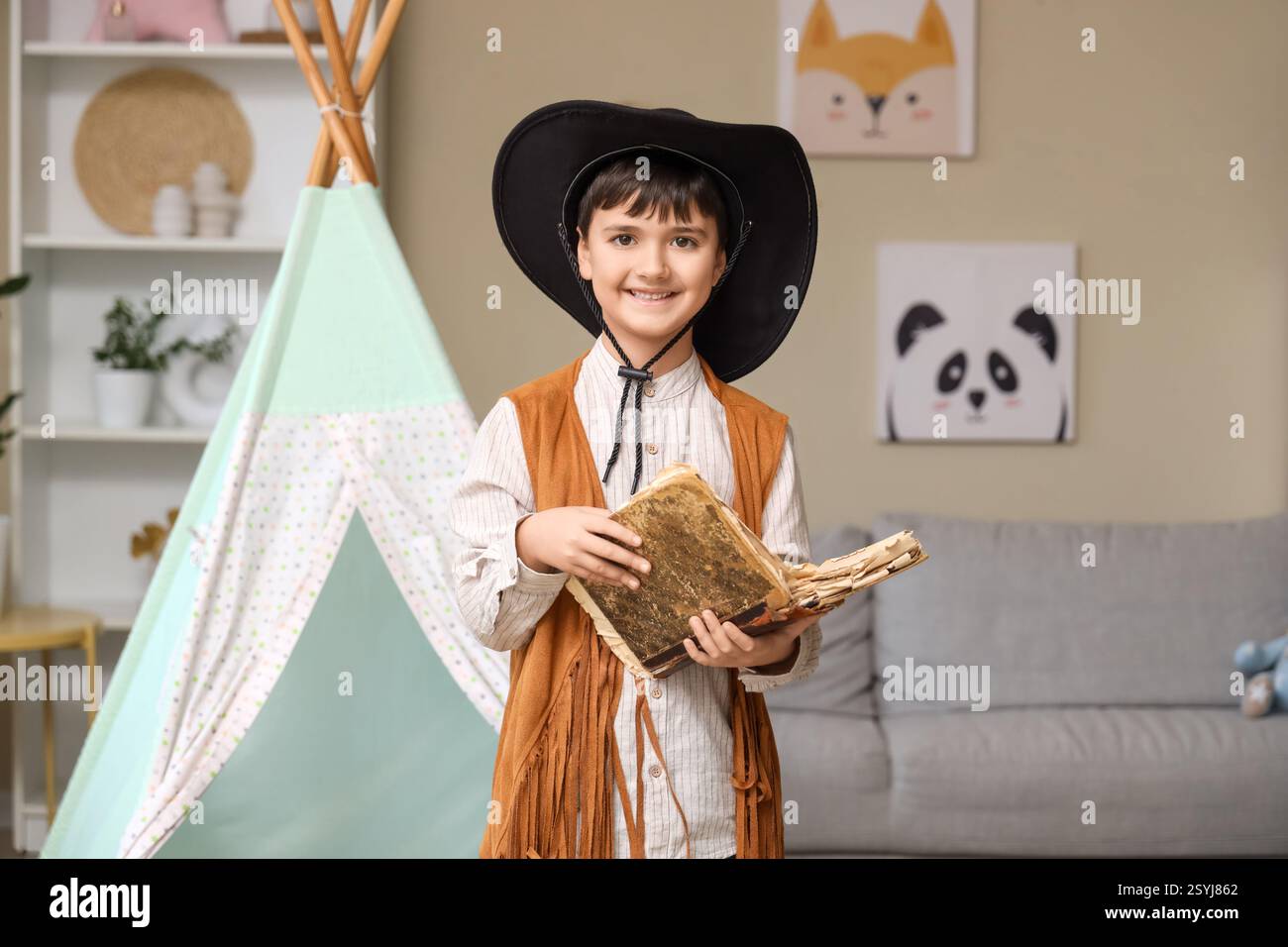 Cute boy dressed as cowboy reading adventure book at home Stock Photo ...