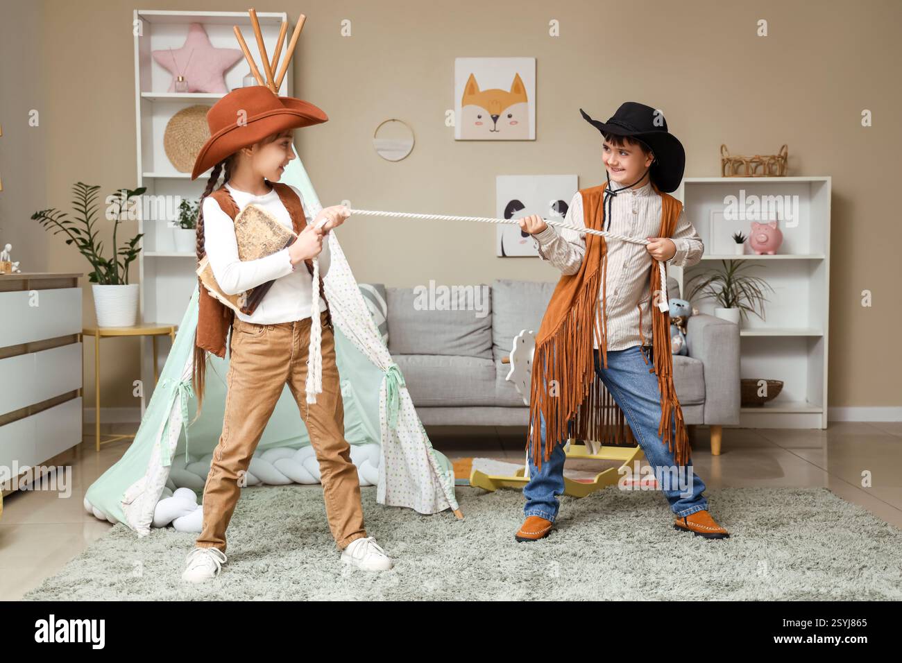 Cute children dressed as cowboys with rope and adventure book at home ...