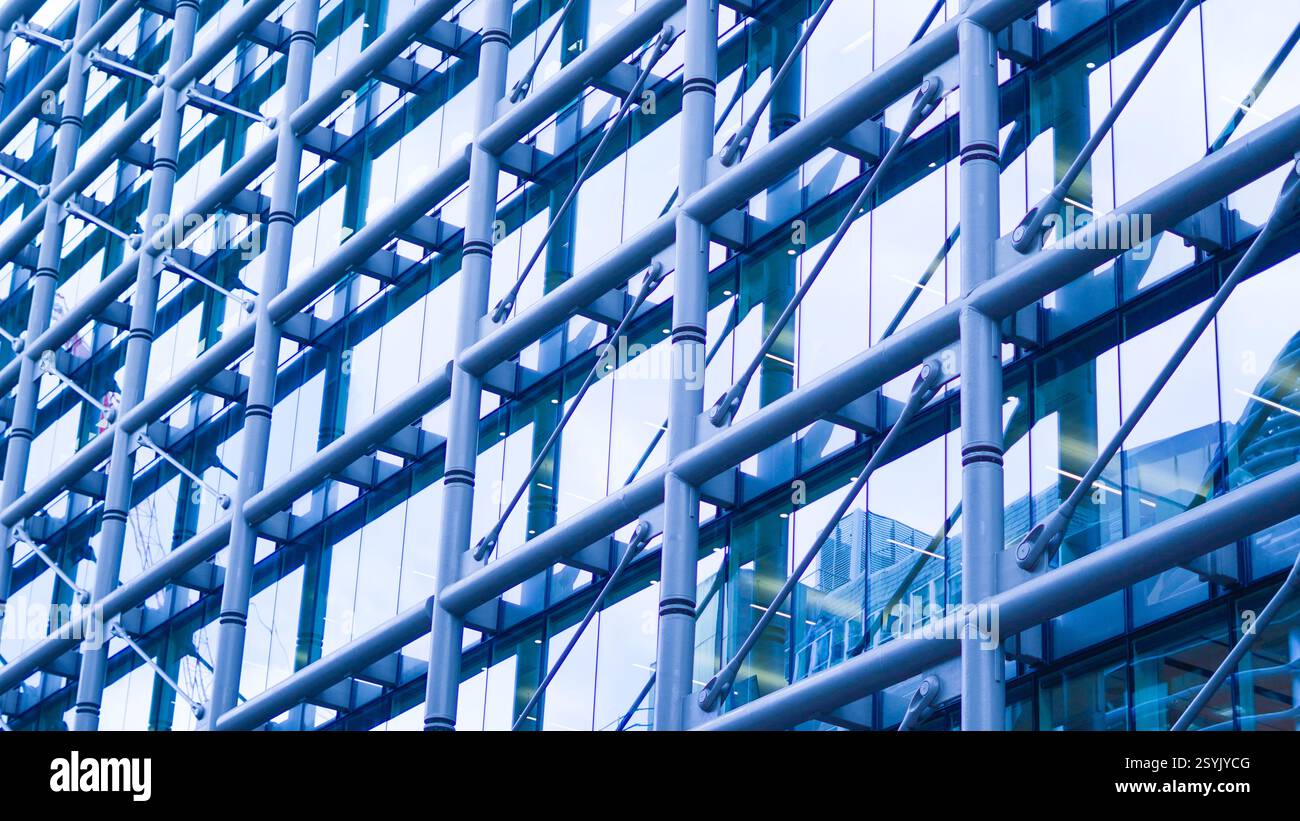 Towering blue glass skyscraper reflecting sky and city buildings below ...