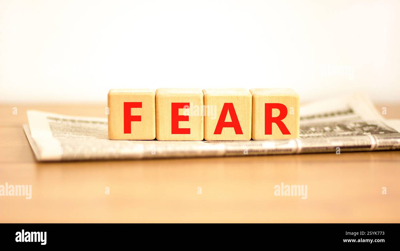 Fear symbol. Concept word Fear on beautiful wooden blocks on newspaper. Beautiful wooden table ...