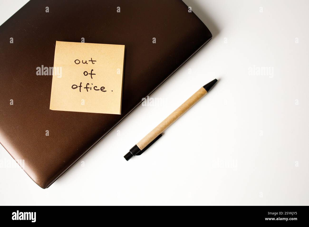 Sticky note with handwritten phrase out of office on a laptop with pen ...