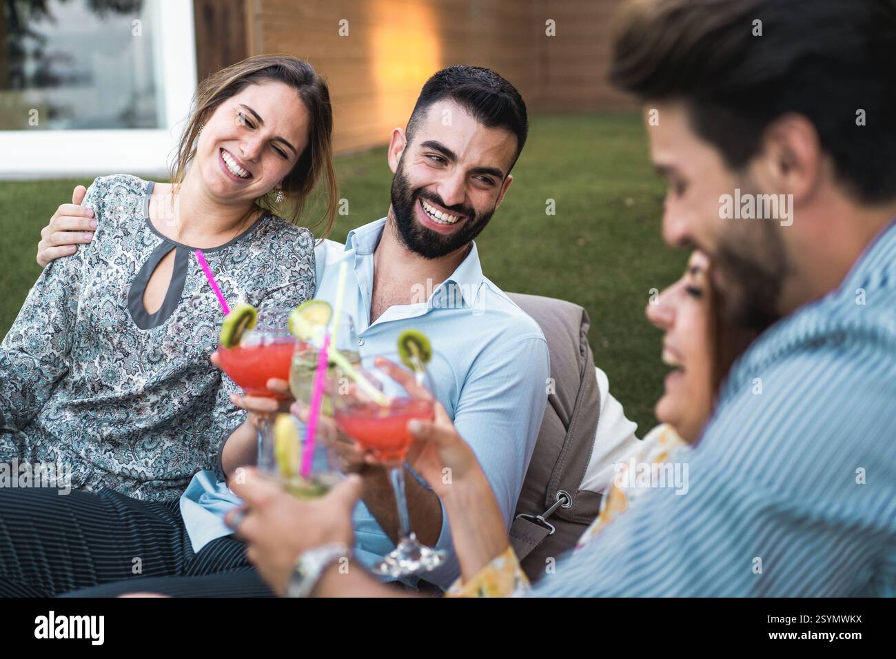 A group of cheerful friends enjoying cocktails and toasting together at ...