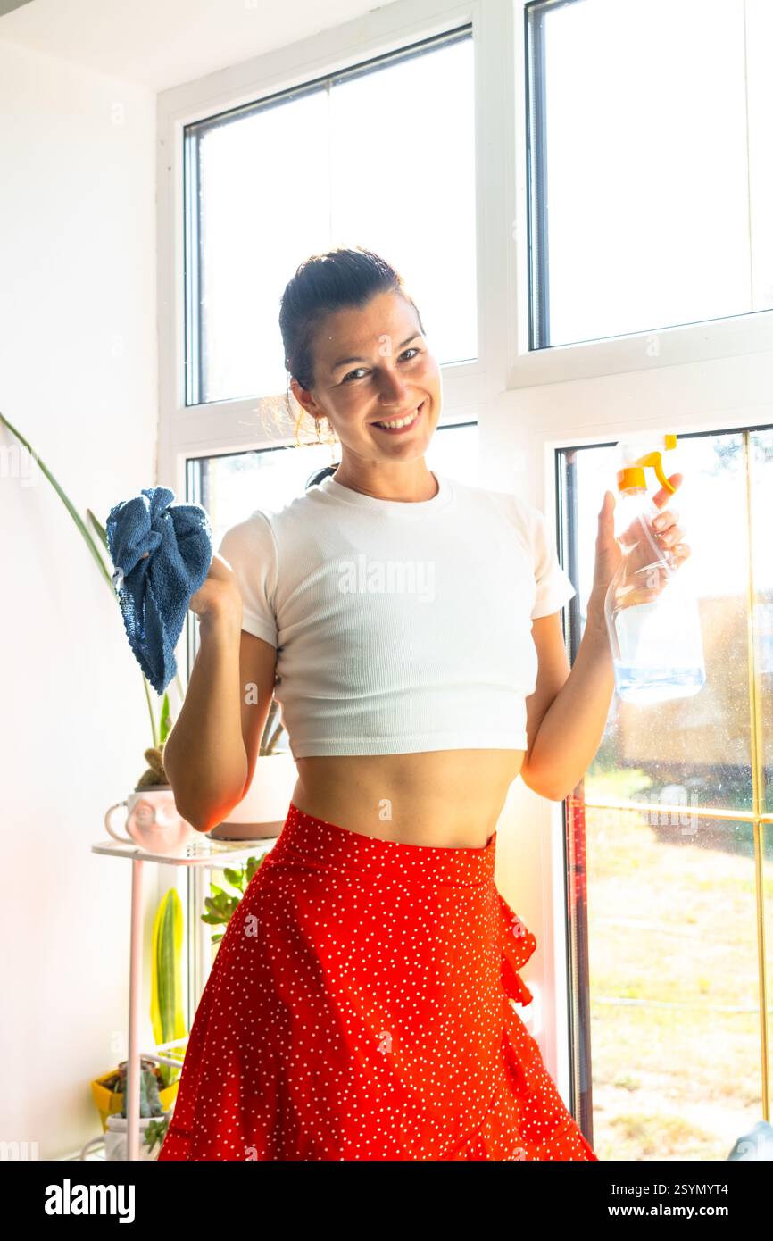 Portrait Woman with detergent, manually washes window of house with rag ...