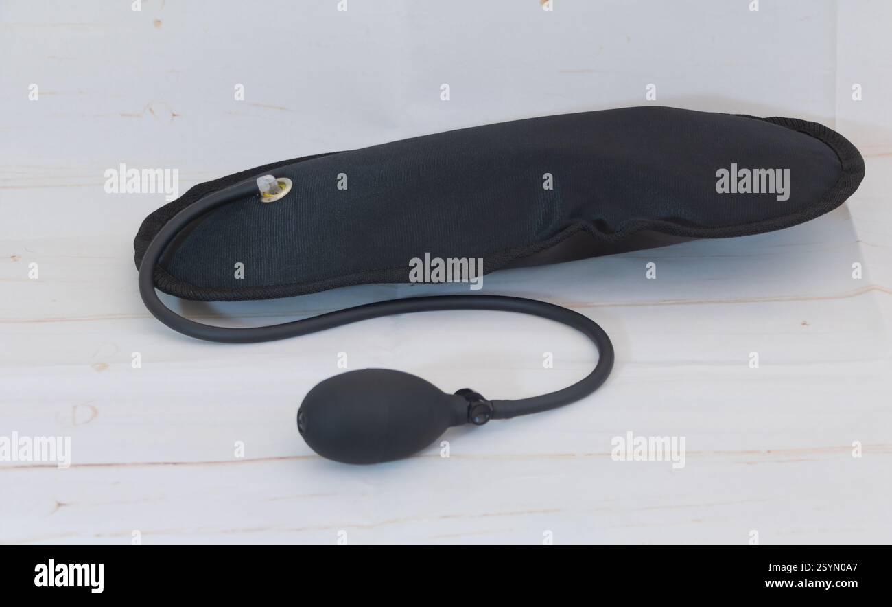 A black air cushion with an elongated rubber tube attached to it, lying ...