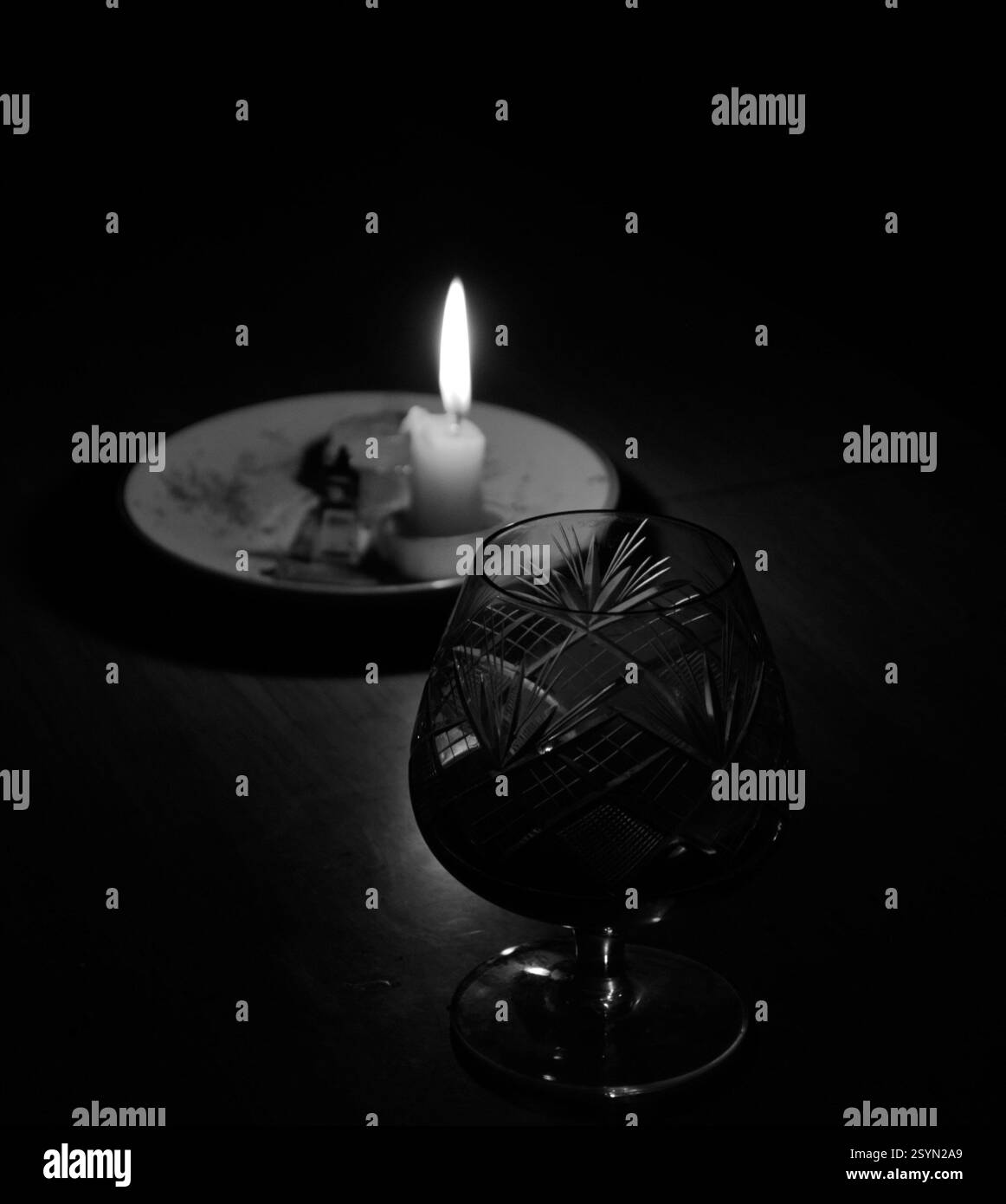 A glass of brandy dimly illuminated by candlelight. High contrast ...