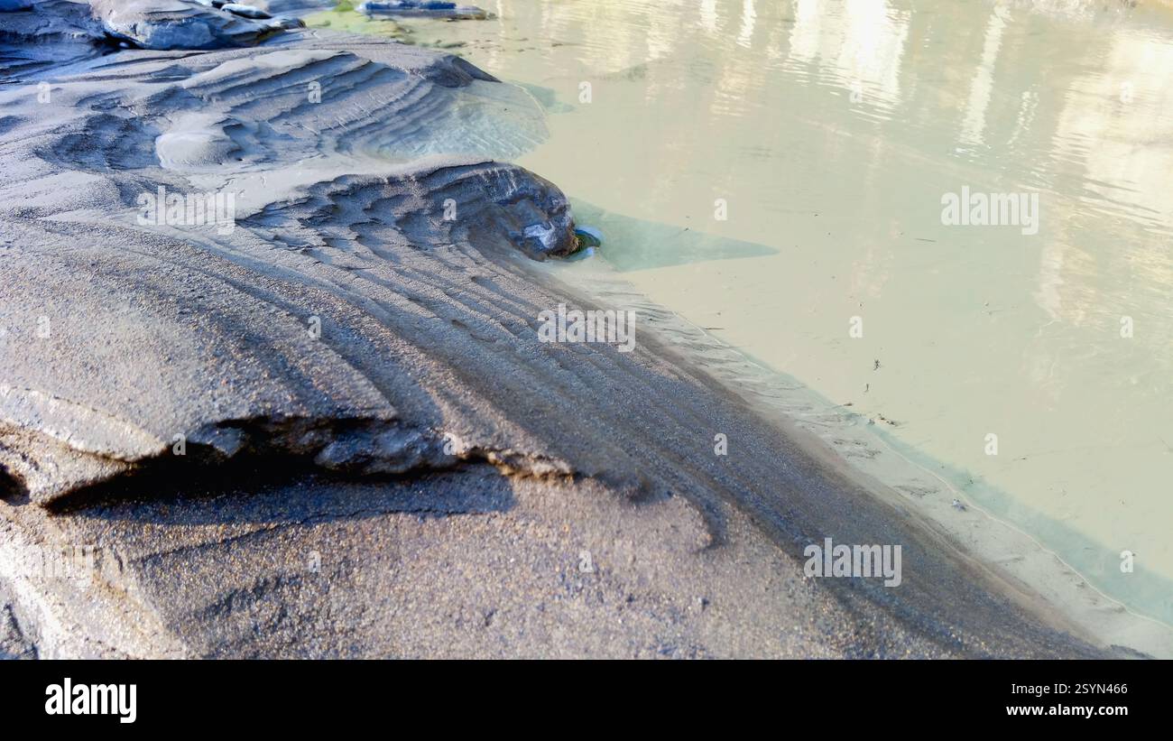 Clear green river water and layered clay riverbank in morning. Light ...