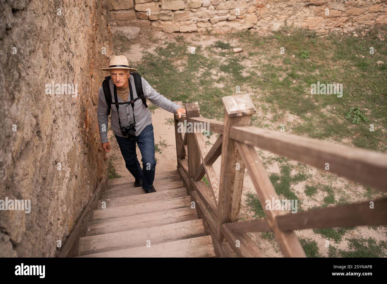 Male retired tourist with backpack climbing stairs exploring ancient ...