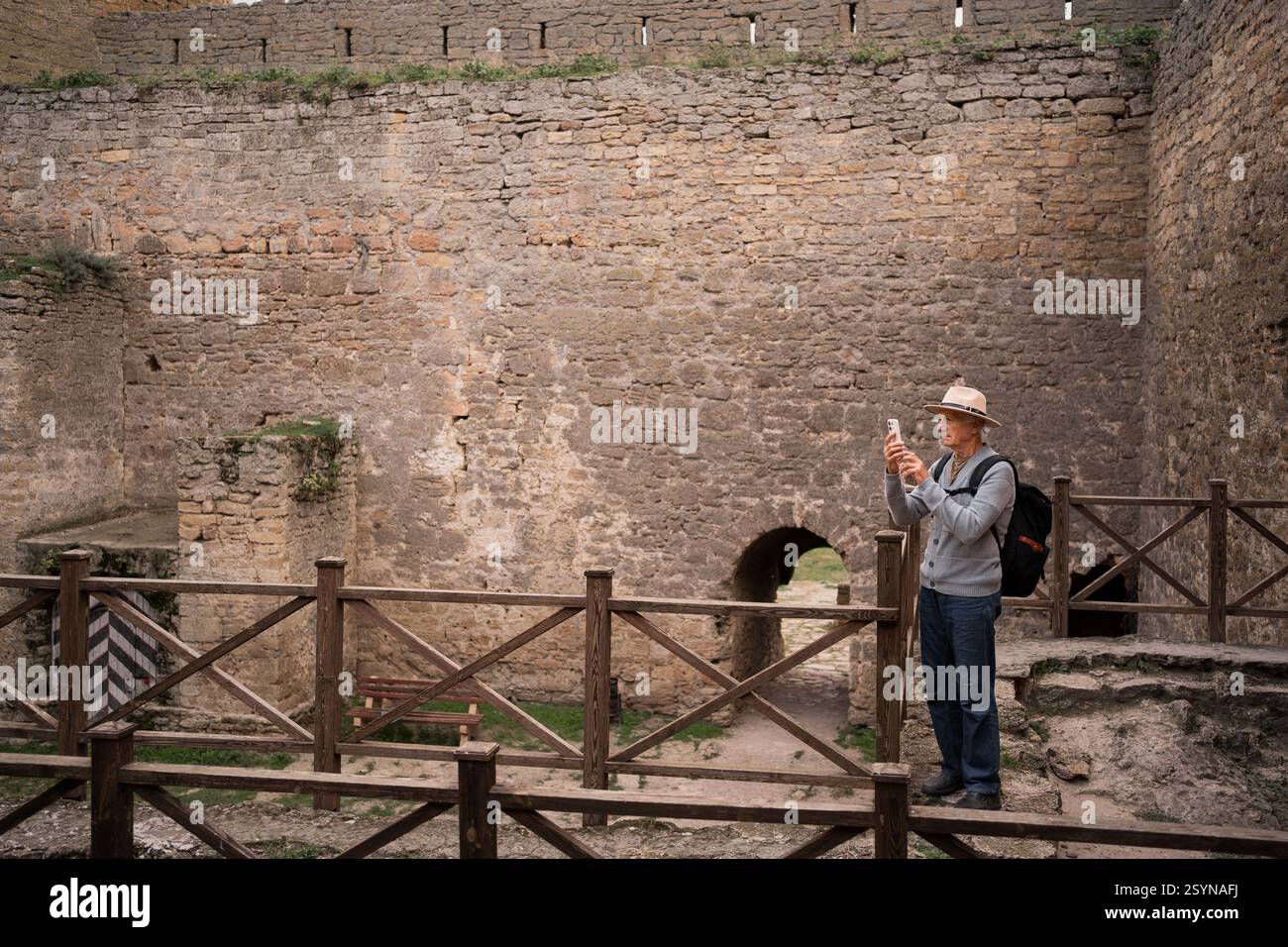 Elderly man in hat visiting medieval fortress taking photo for memory ...