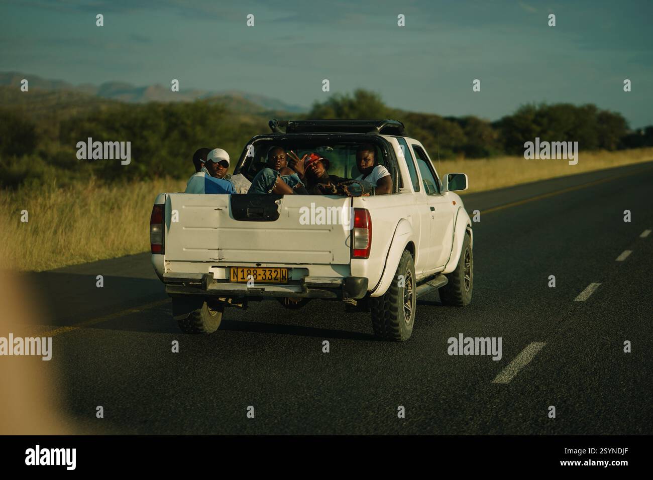 Windhoek, Namibia - April 29, 2024. Pickup truck moving along the road with people sitting in ...