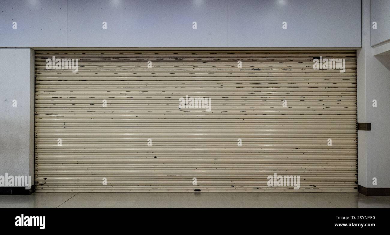 Closed shuttered and abandoned shopfront in a major UK shopping mall ...