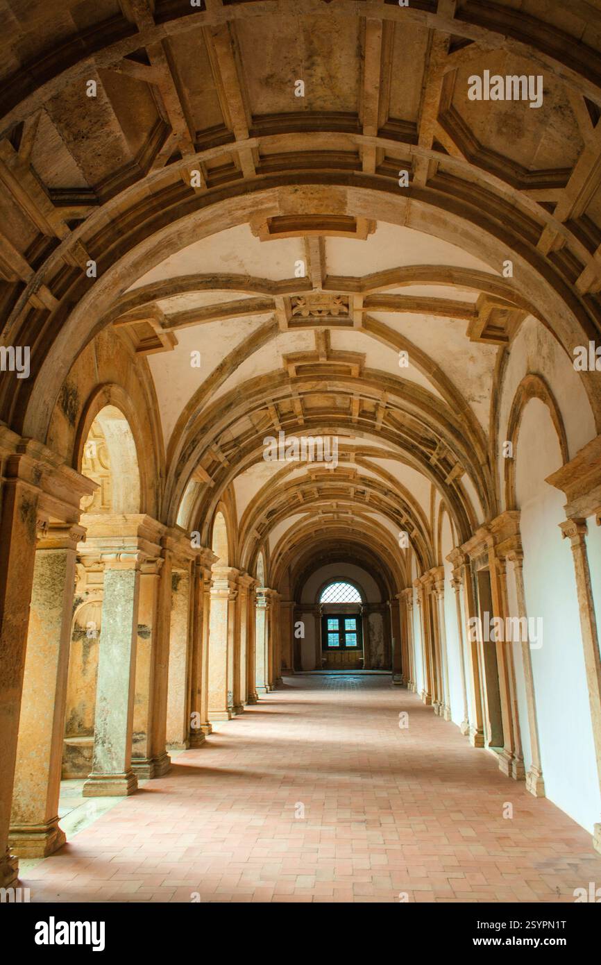 view down a long, arched corridor with a vaulted ceiling, illuminated ...