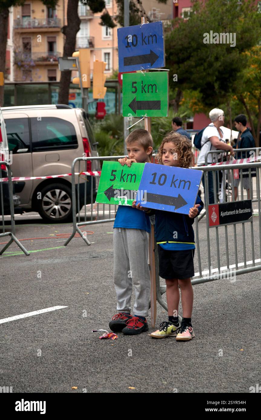 Cute girl and boy with directional signs in marathon in Gracia ...