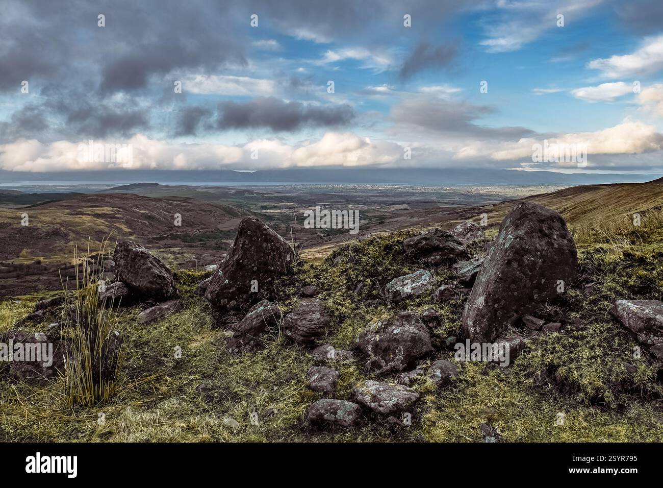 Elevated view. Numerous gray rocks scattered on a grassy hill. Distant ...