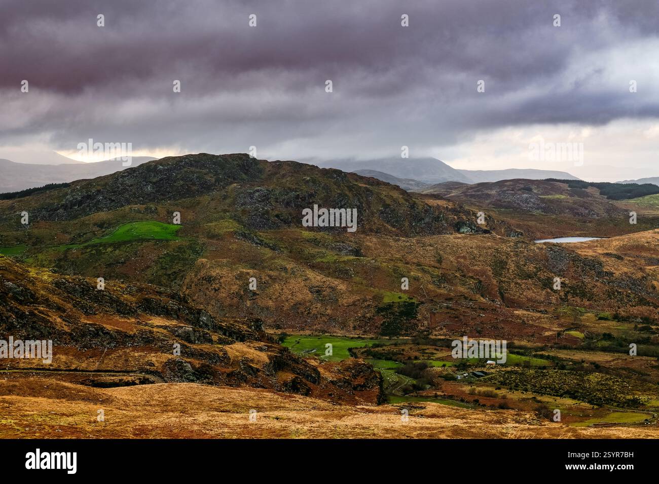 Overcast clouds loom over rugged mountains, revealing a mix of browns ...