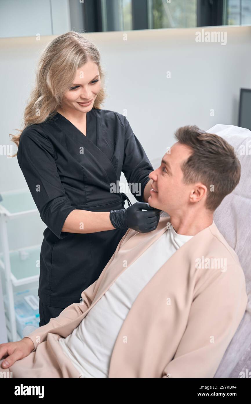 Skilled cosmetologist examining male client face skin, cosmetic ...