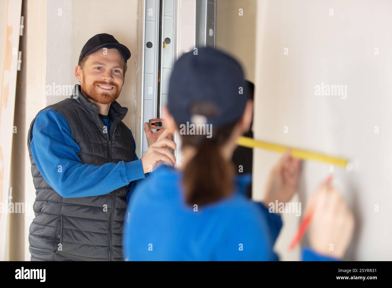 builders measuring a wall using a tape measure Stock Photo - Alamy