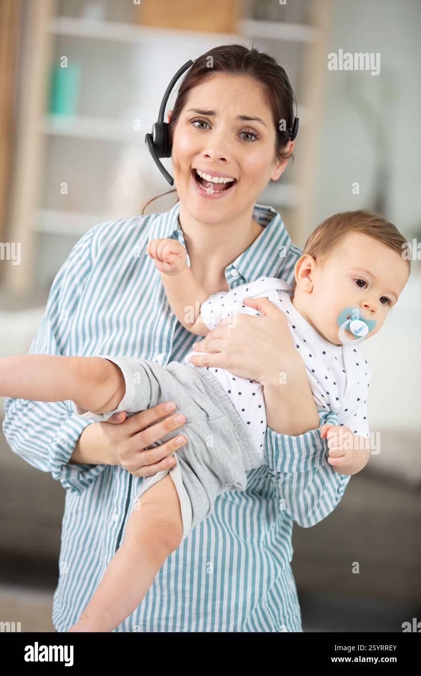 mother using telephone with baby in arms Stock Photo - Alamy