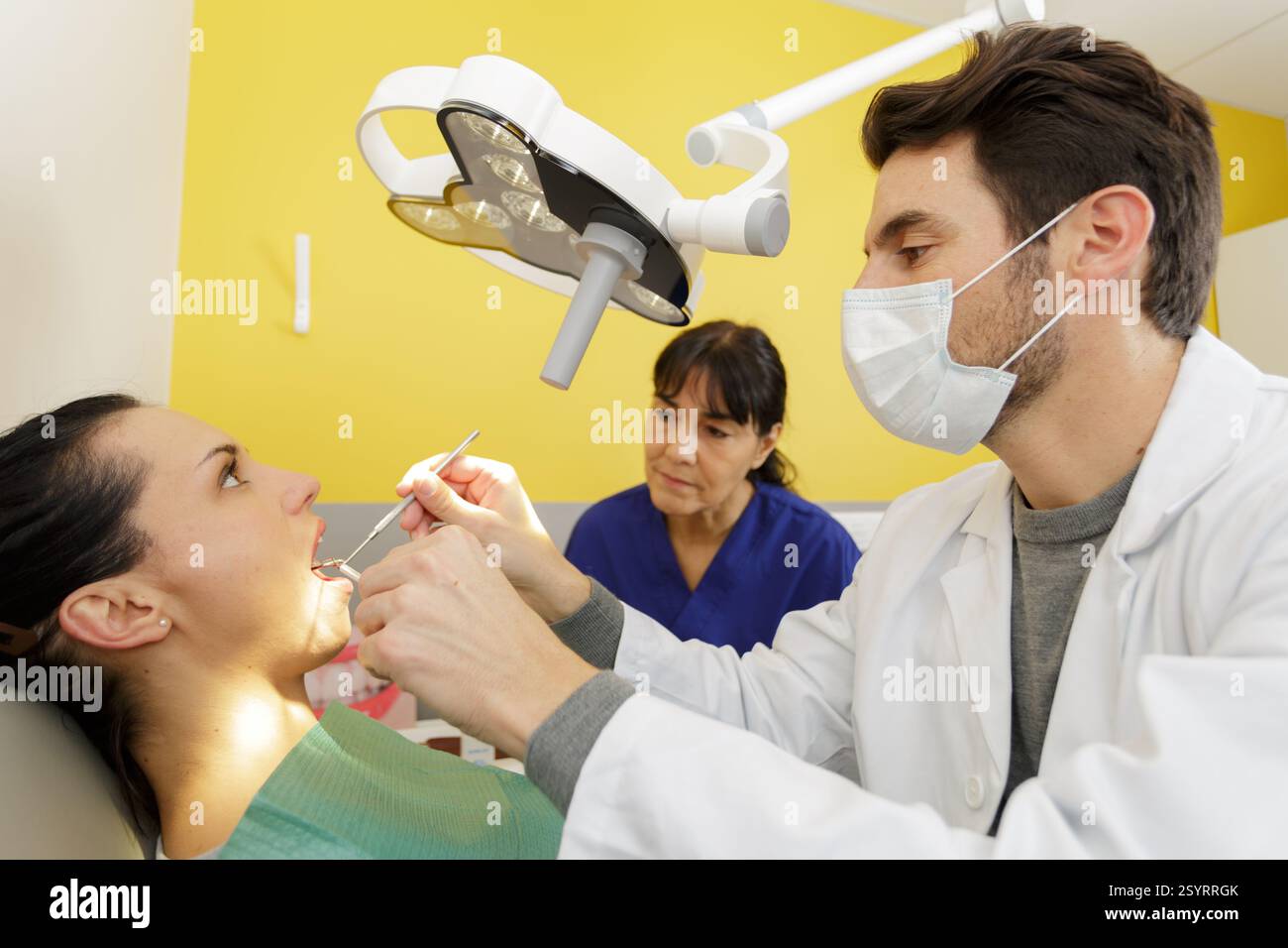 male dentist inspecting female patients teeth Stock Photo - Alamy