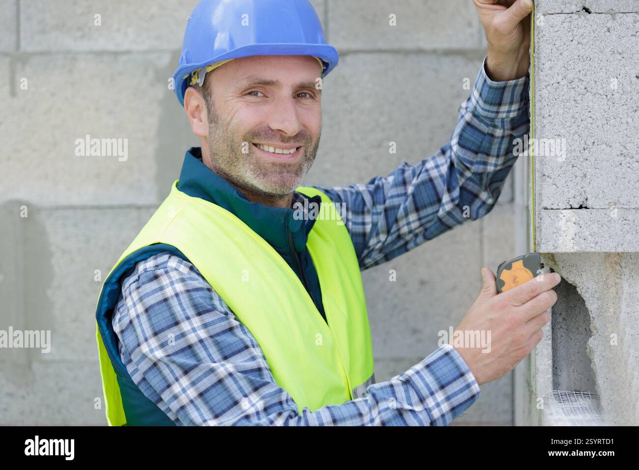 worker checks erected brick wall with level Stock Photo - Alamy