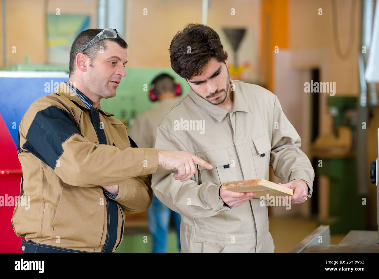 supervisor pointing to plank of wood held by apprentice Stock Photo - Alamy