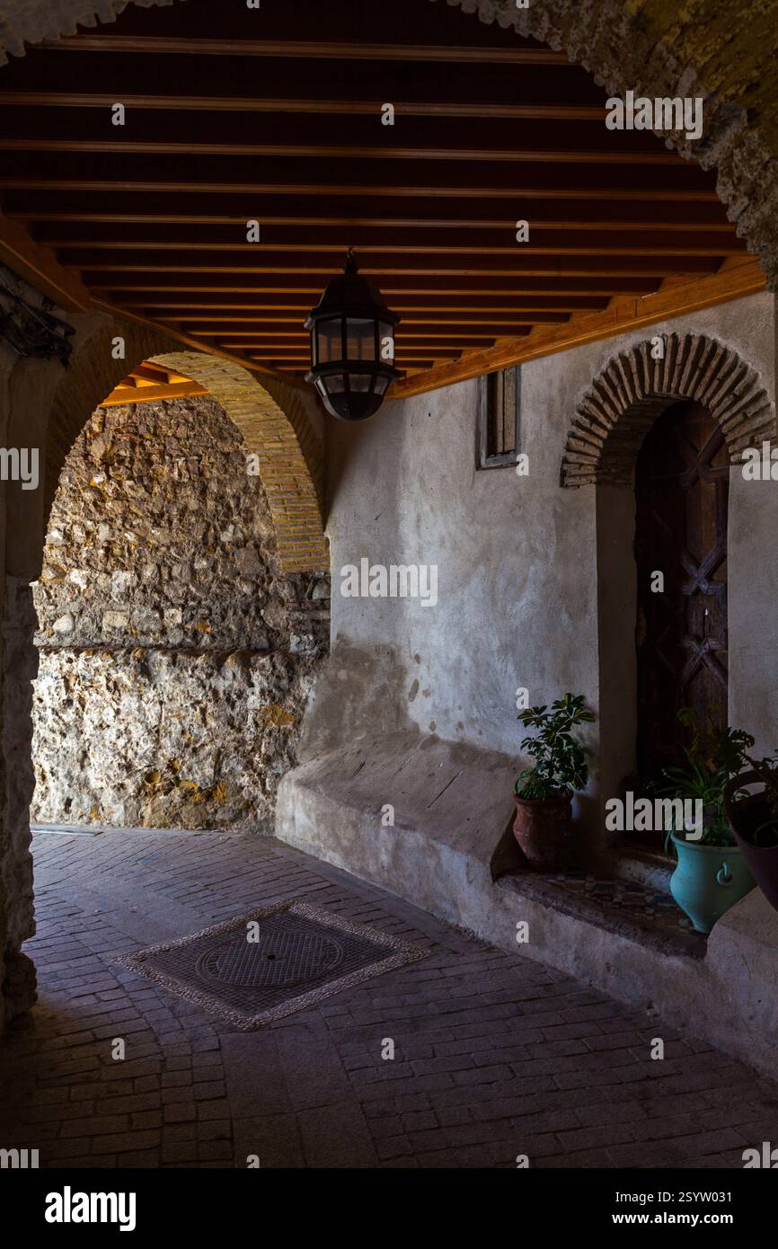 dimly lit passageway with arched stone walls, a lantern casting a warm ...