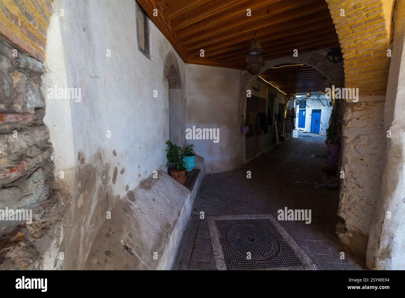 dimly lit passageway with arched stone walls, a lantern casting a warm ...
