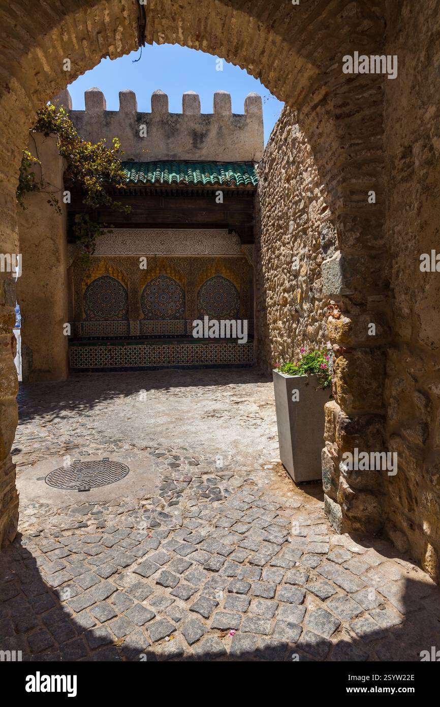 a stone archway, leading towards a courtyard adorned with colorful ...