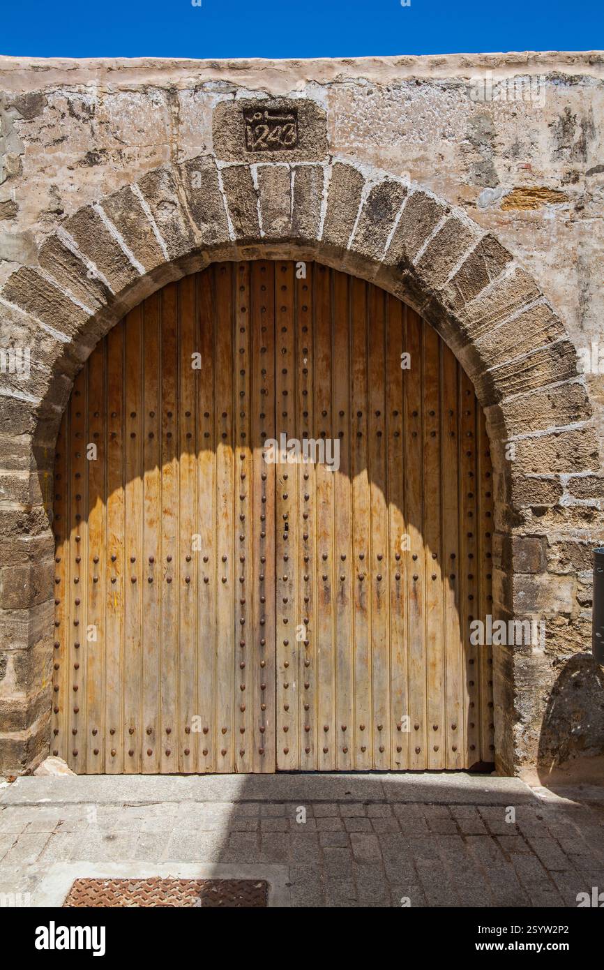 weathered wooden door with an arched stone frame and a keystone marked ...