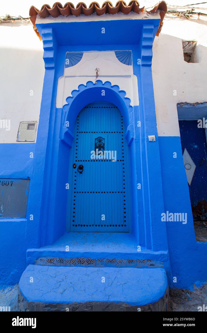 blue arched door with decorative details and a small window, set within ...