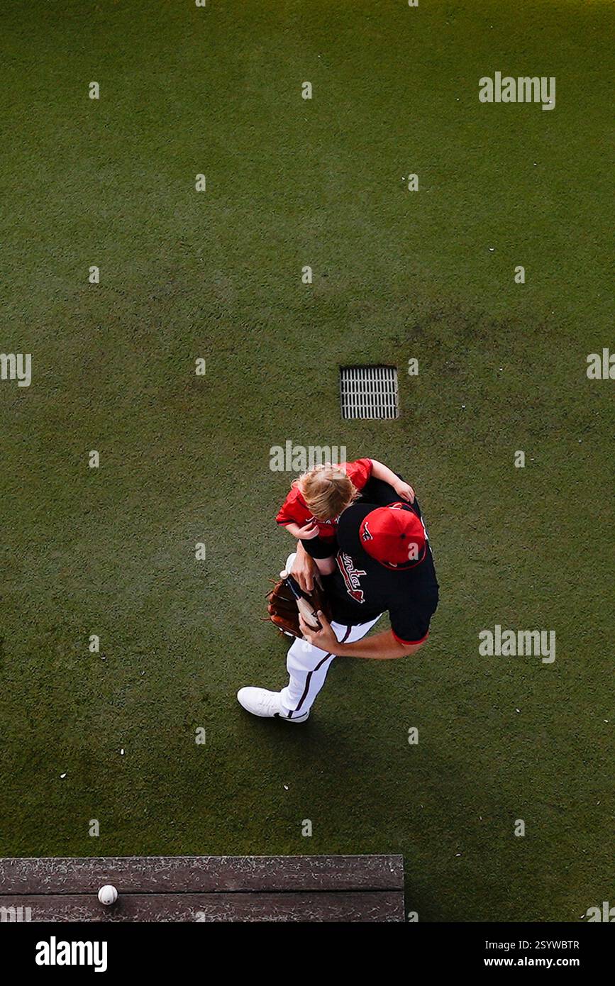 Atlanta Braves pitcher Dylan Lee walks in the bullpen holding a child ...