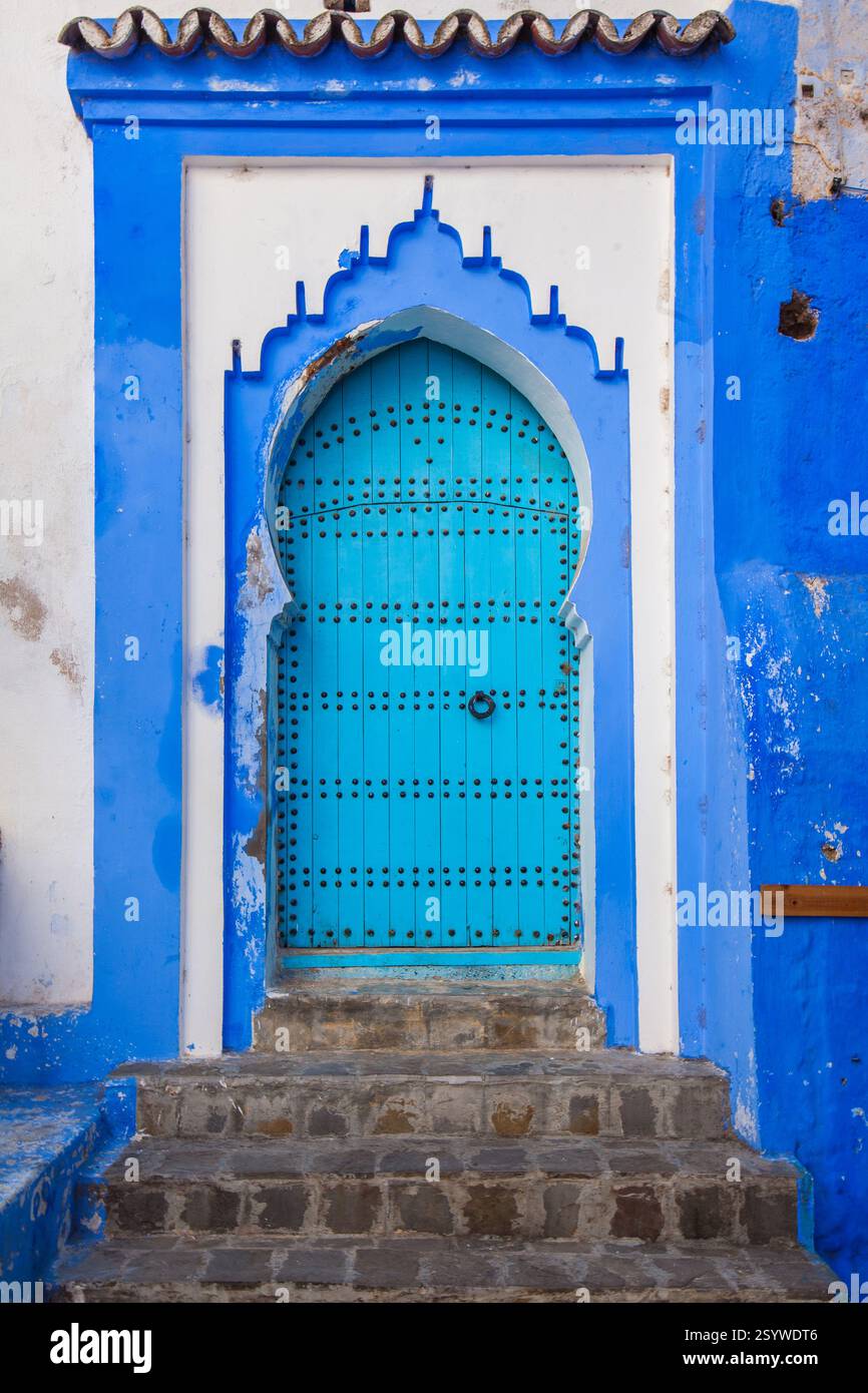 vibrant blue studded door with a curved archway, framed by white and ...