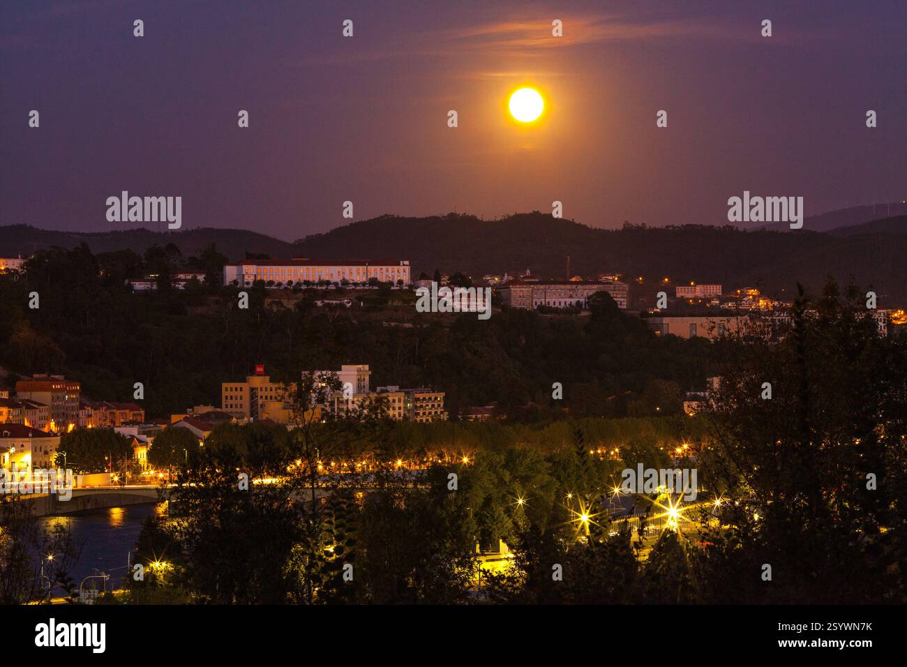 A bright full moon illuminates the night sky over a cityscape with ...
