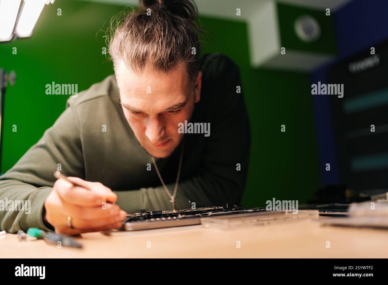 Closeup portrait of skilled technician using tweezers repairing laptop motherboard components in ...