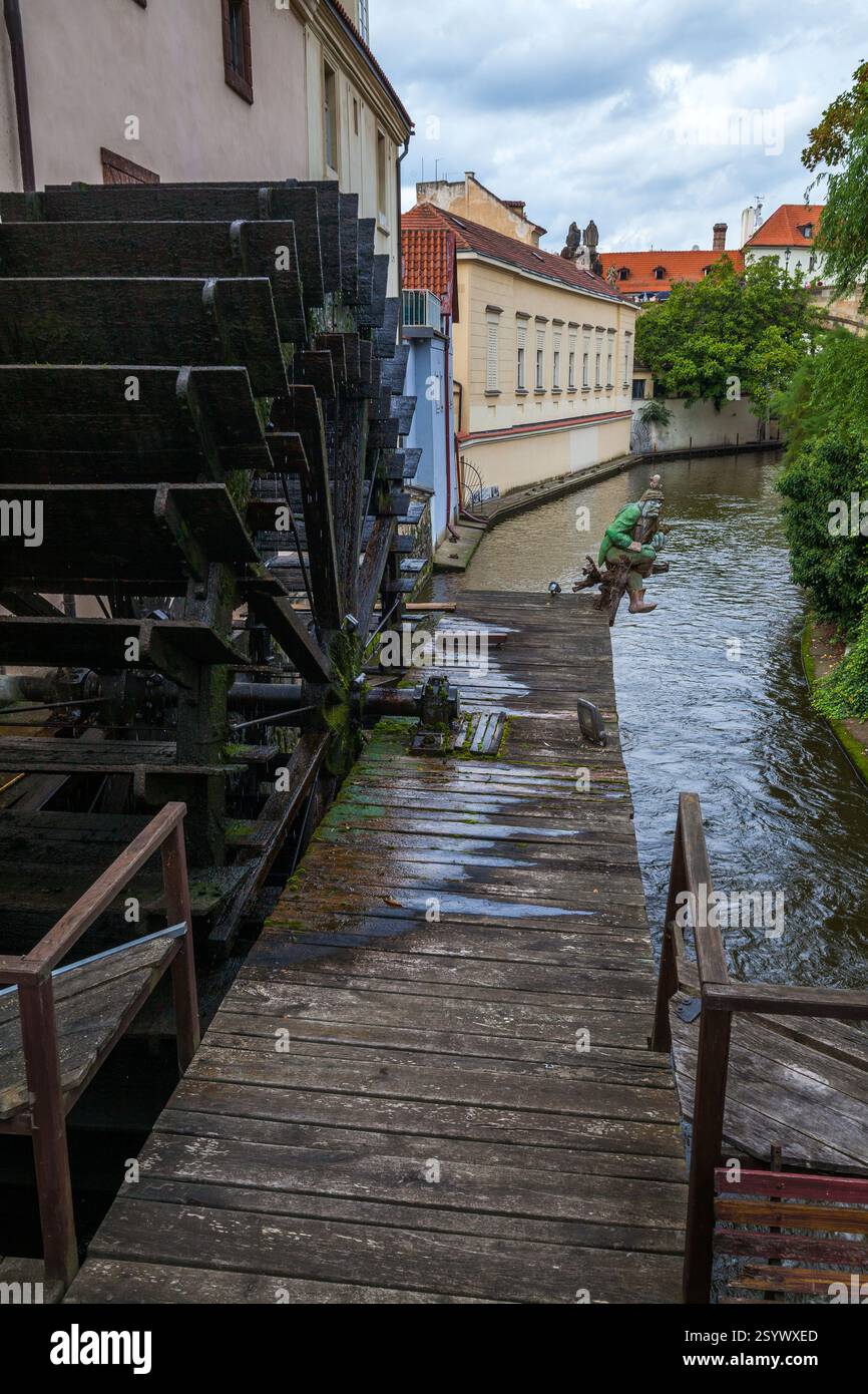 A historic watermill with a large wooden wheel sits beside a canal in ...