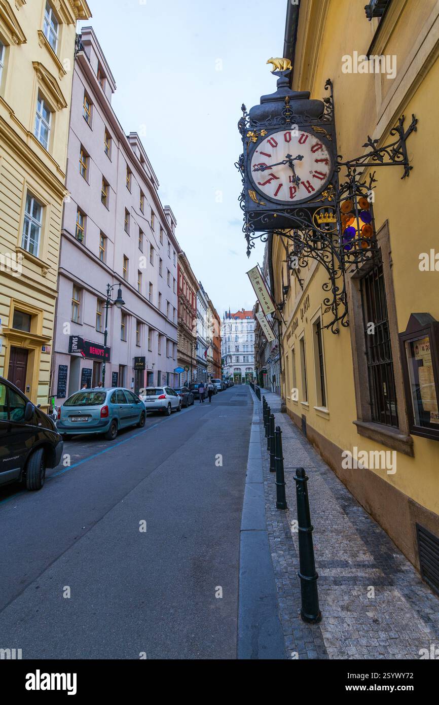 A charming European street scene features a vintage clock hanging from ...