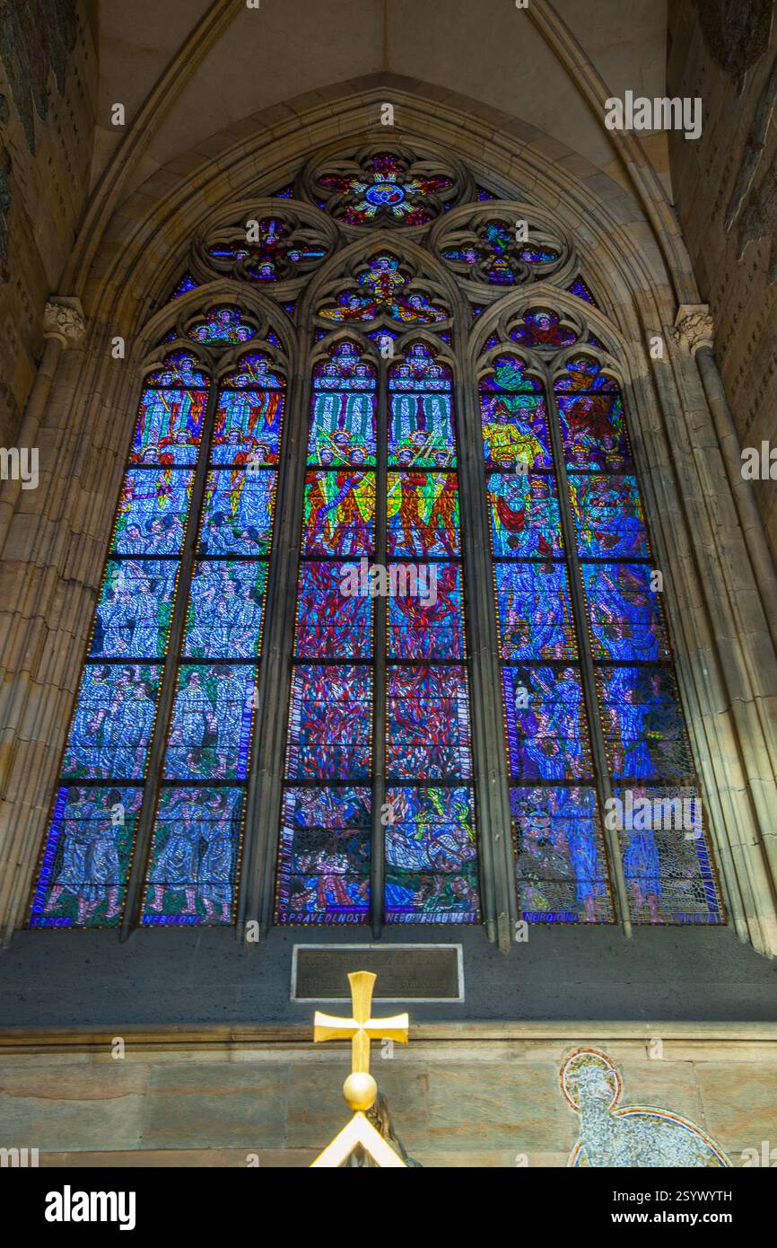 A vibrant stained glass window with intricate patterns and figures fills a gothic archway ...