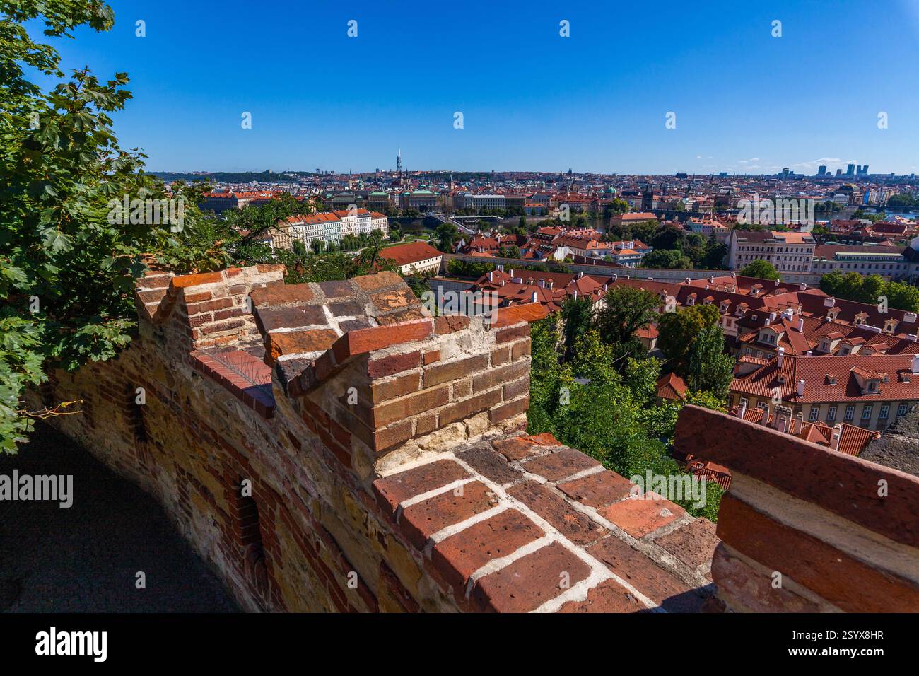 A brick wall with a cityscape view featuring red rooftops, buildings ...