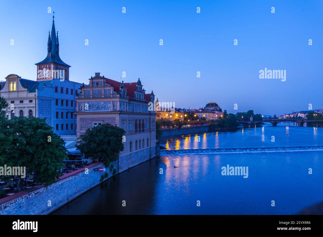 A waterfront cityscape at twilight, featuring a building with a clock ...