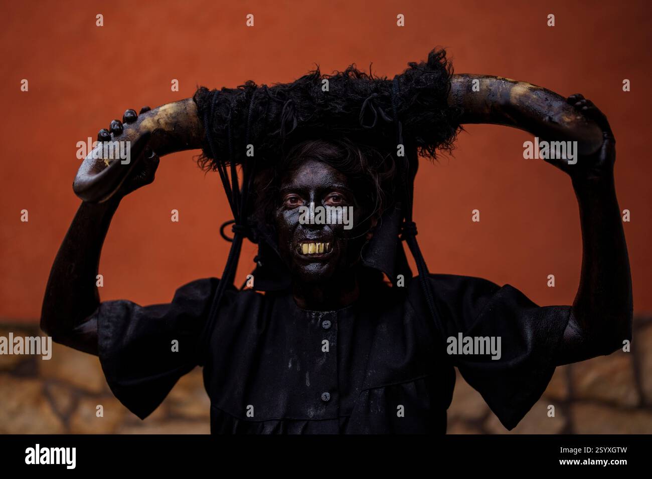 A reveler, dressed as "Diablos de Luzon" or Luzon Devil's, covered in ...