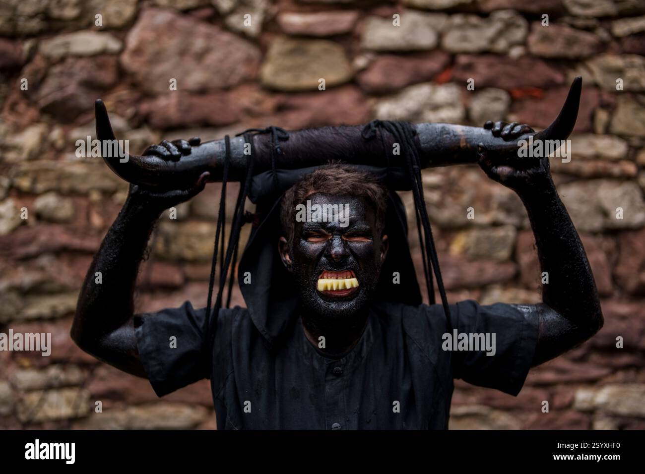 A reveler, dressed as "Diablos de Luzon" or Luzon Devil's, covered in ...