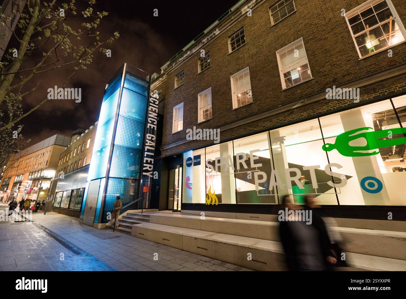 Night view of the Science Gallery, London, UK. People walk by the ...