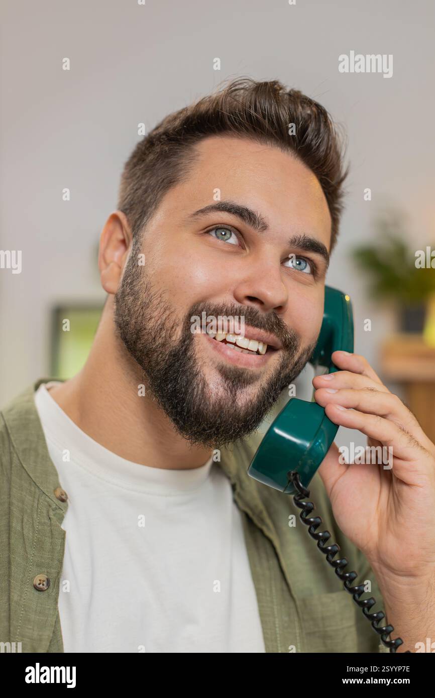 Closeup of smiling young man making wired telephone call conversation ...