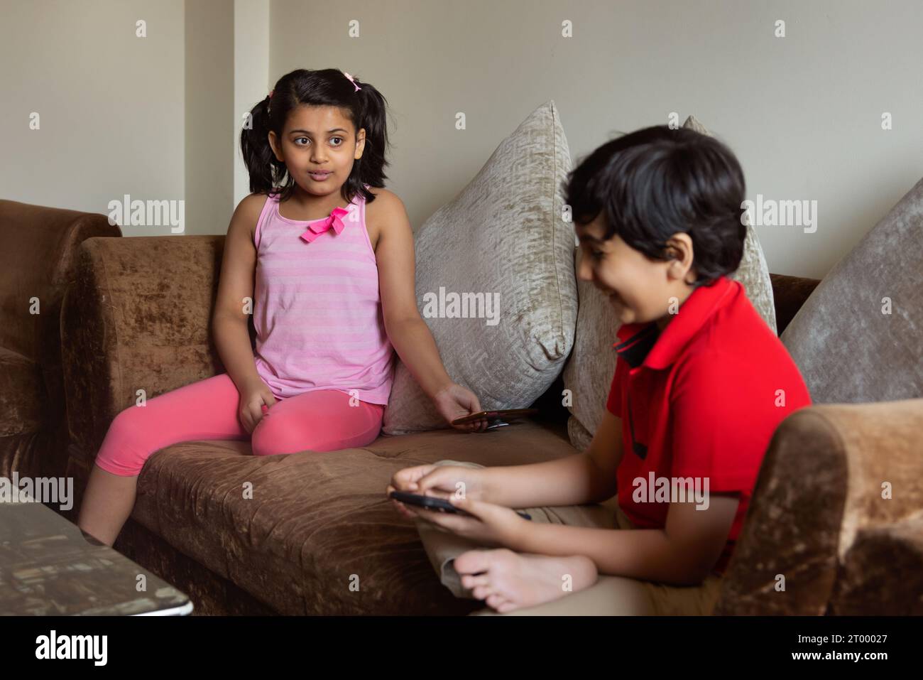 Sibling using mobile phones in living room Stock Photo - Alamy