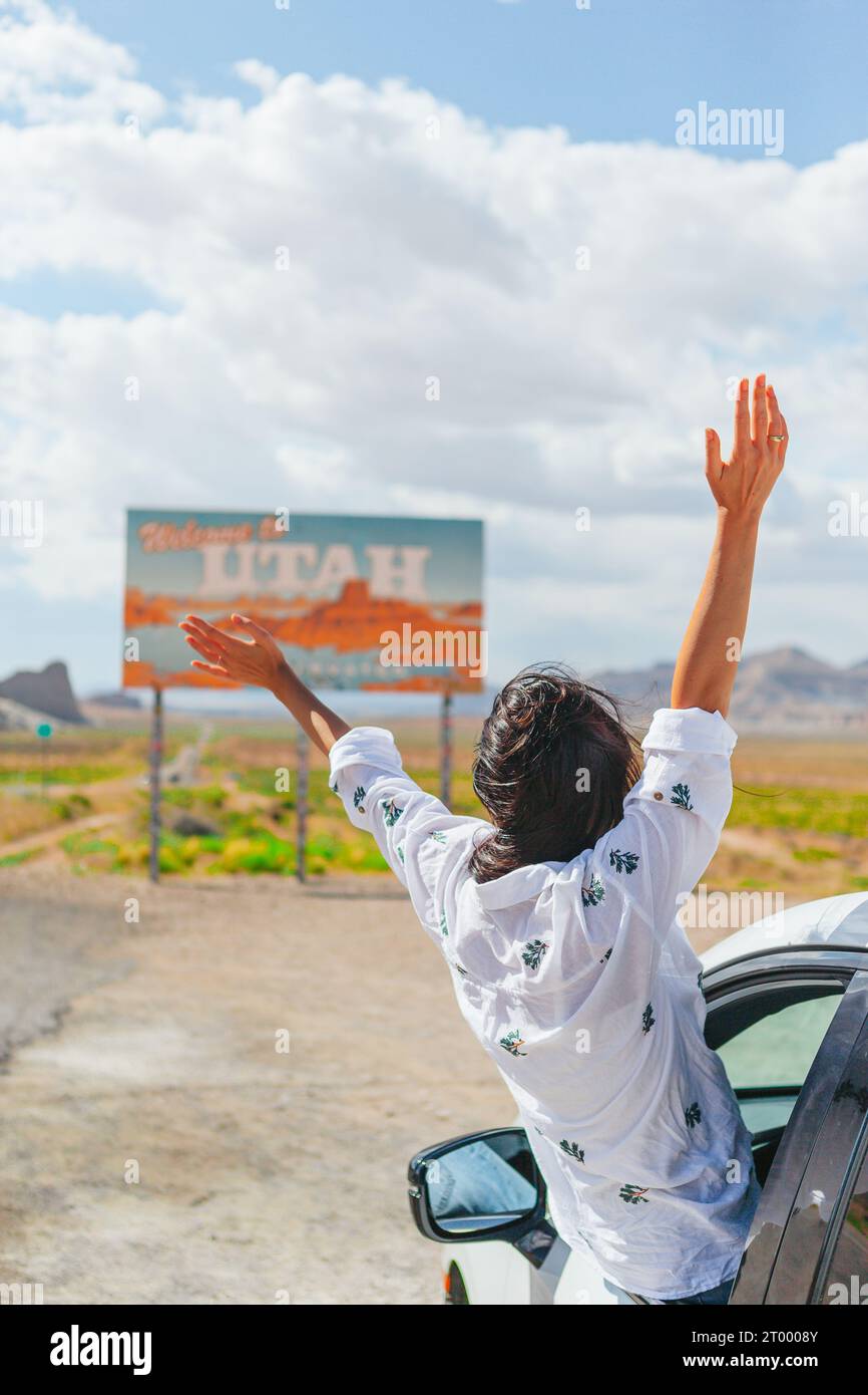 Beautiful woman on her trip by the car. Welcome to Utah road sign ...