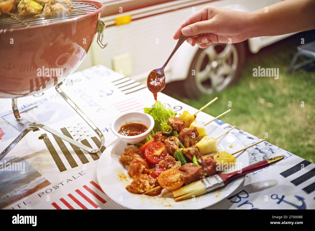 Friends making barbecue BBQ grilling over a hot fire in the nature ...