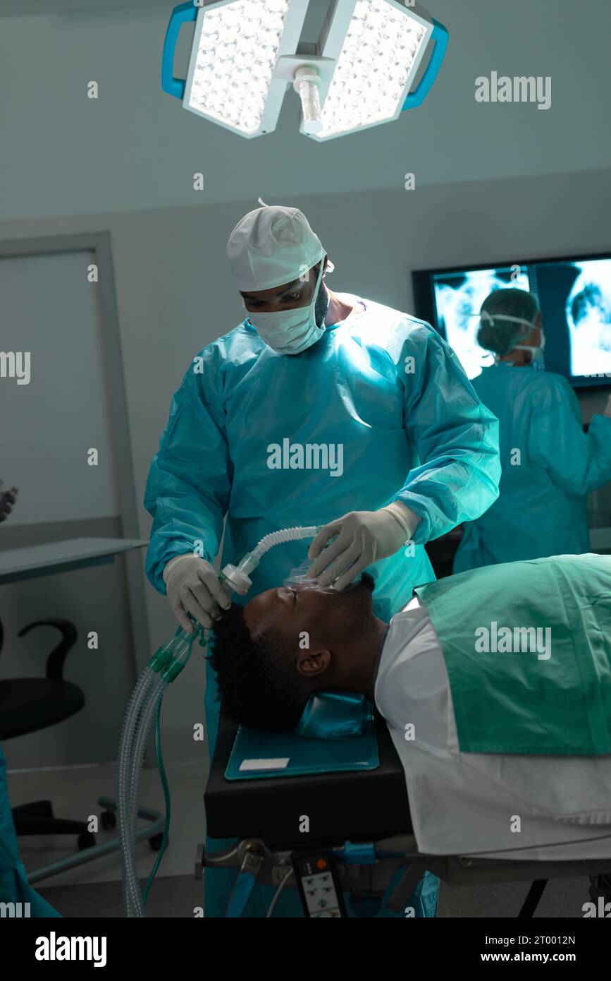 African american surgeon placing anaesthetic face mask on patient in ...