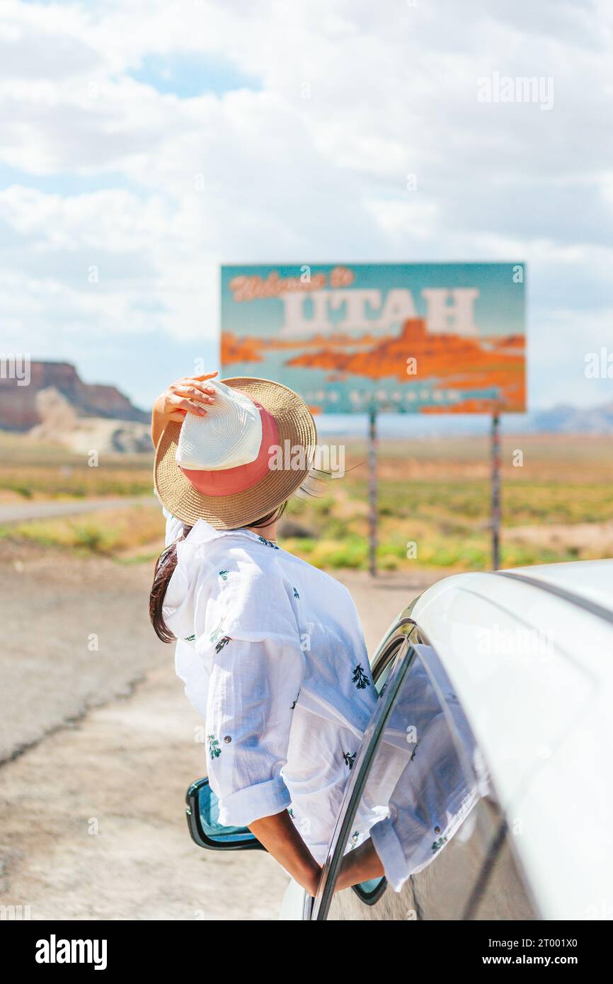 Beautiful woman on her trip by the car. Welcome to Utah road sign ...