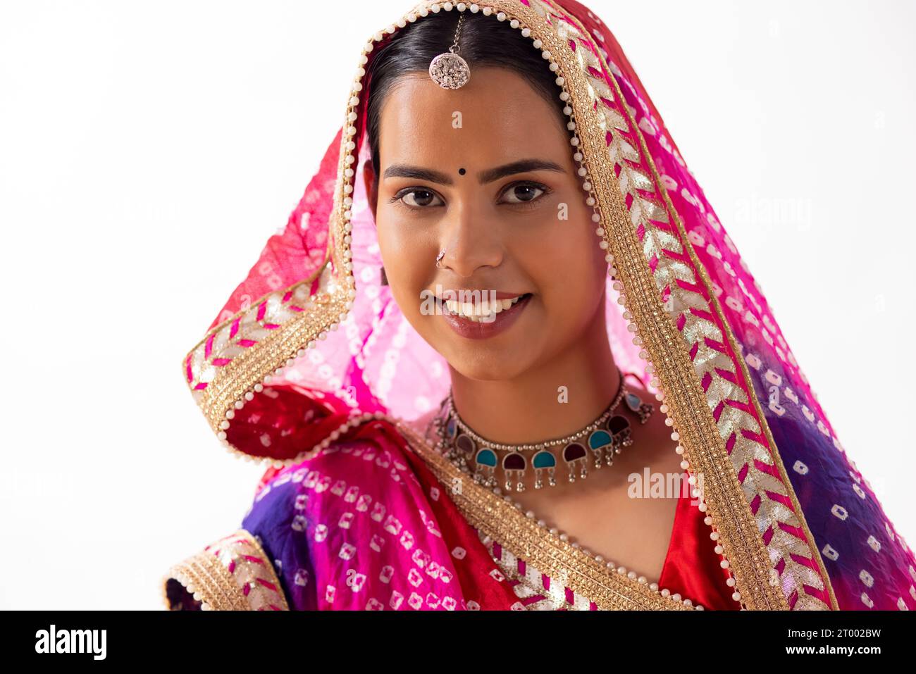 Close-up portrait of a cheerful Rajasthani young woman against white ...